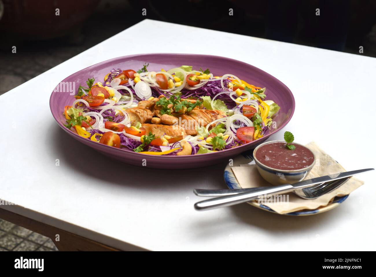 Pan fried chicken on a purple plate with greens and mulberry sauce on ...