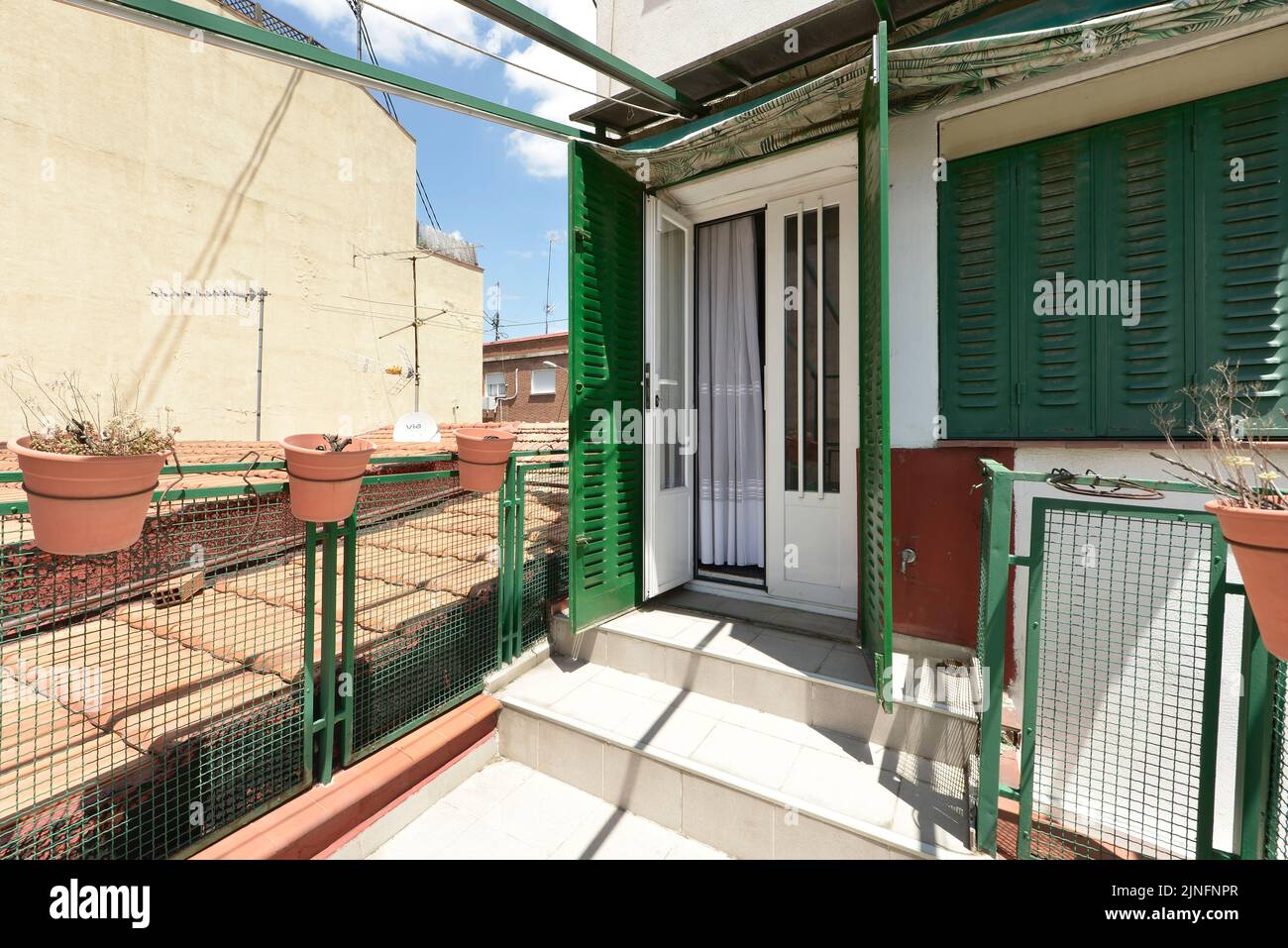 Attic terrace with green metal latticework, clay pots and views of the ...