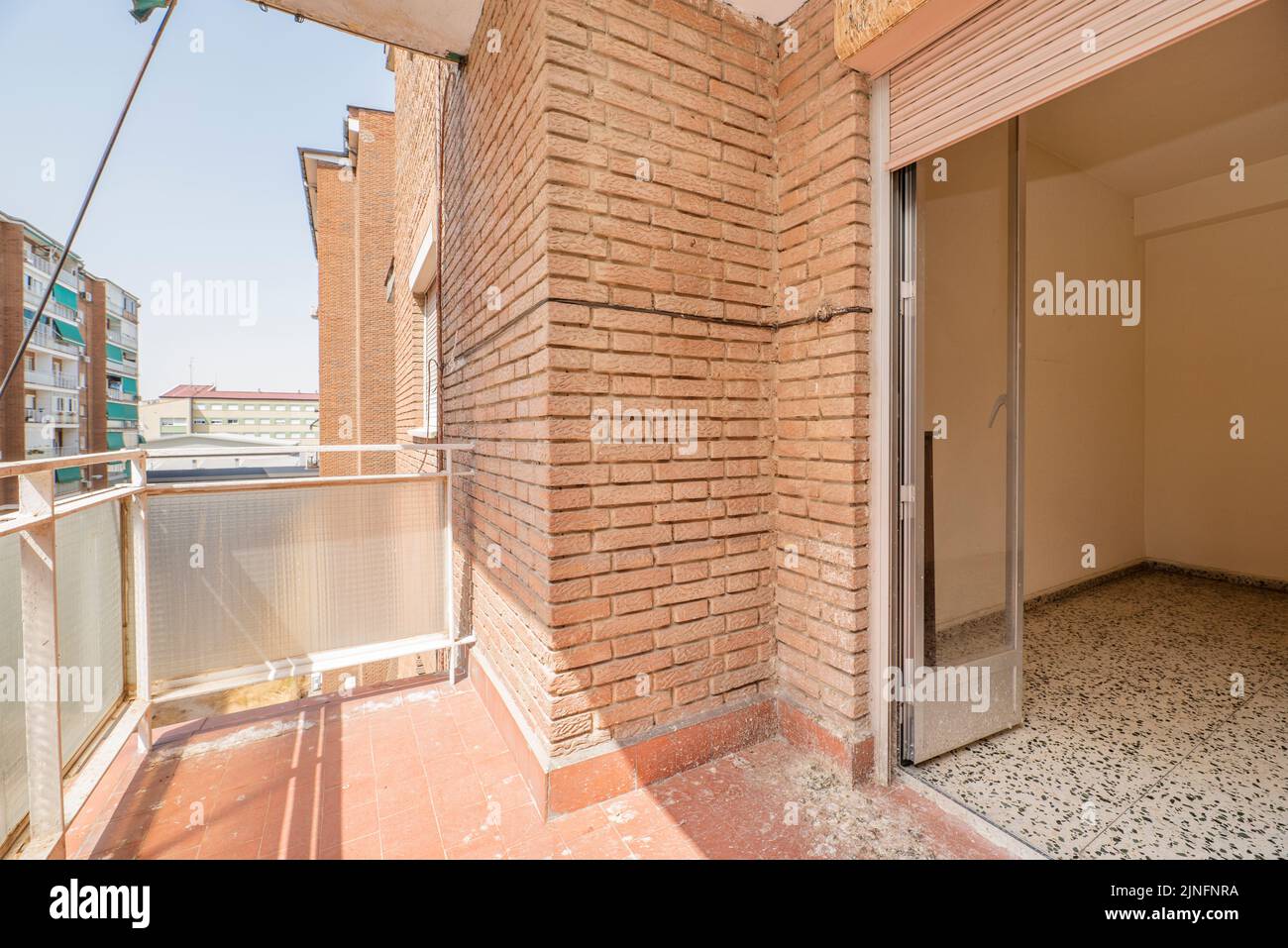 Small empty terrace with exposed brick, clay floors and metal railing ...