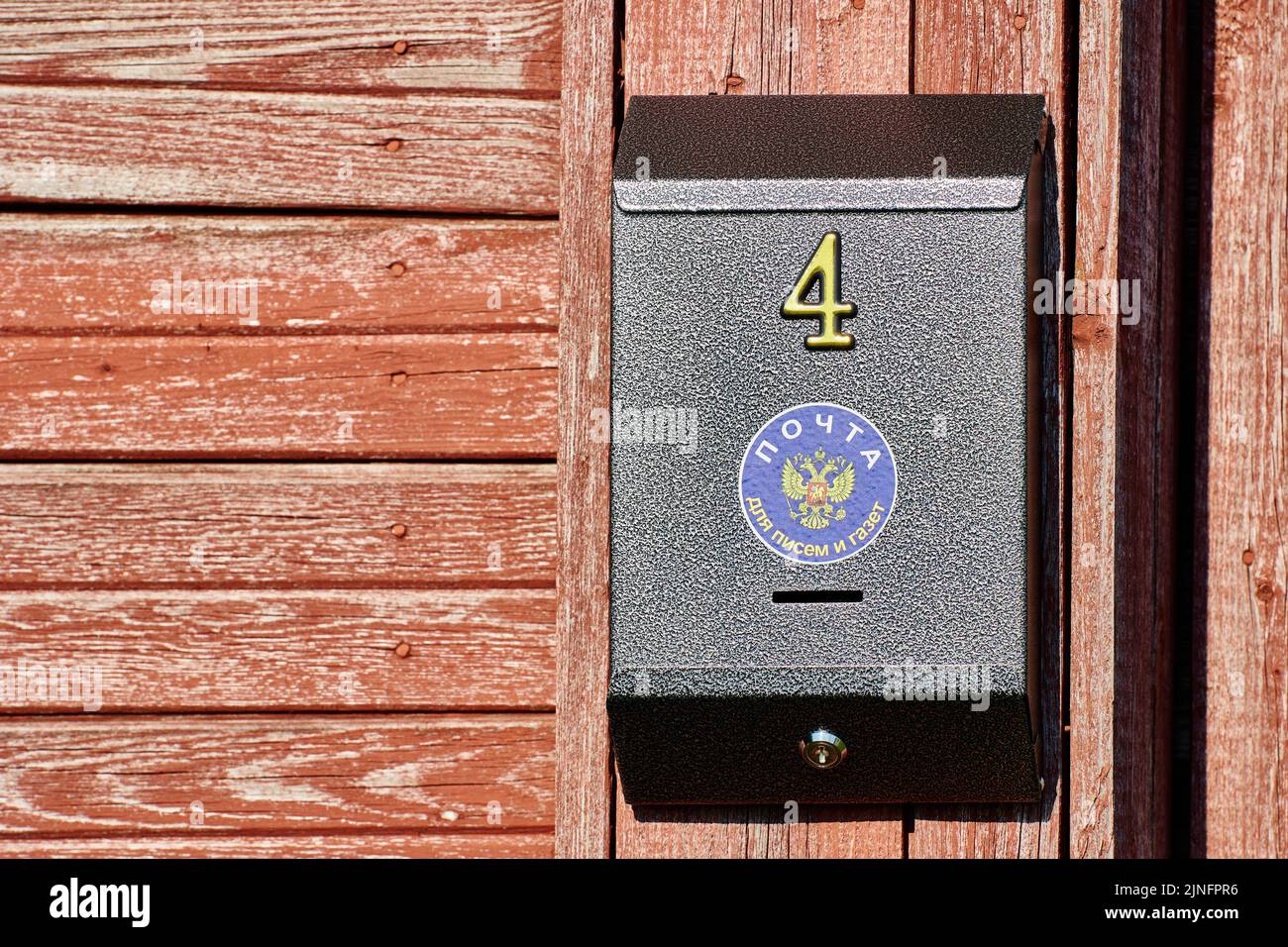 Wall mounted mailbox with number 4 hanging on red wall of an old wooden ...