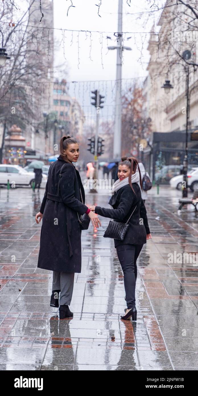 Two attractive and beautiful women are walking together on the rain ...