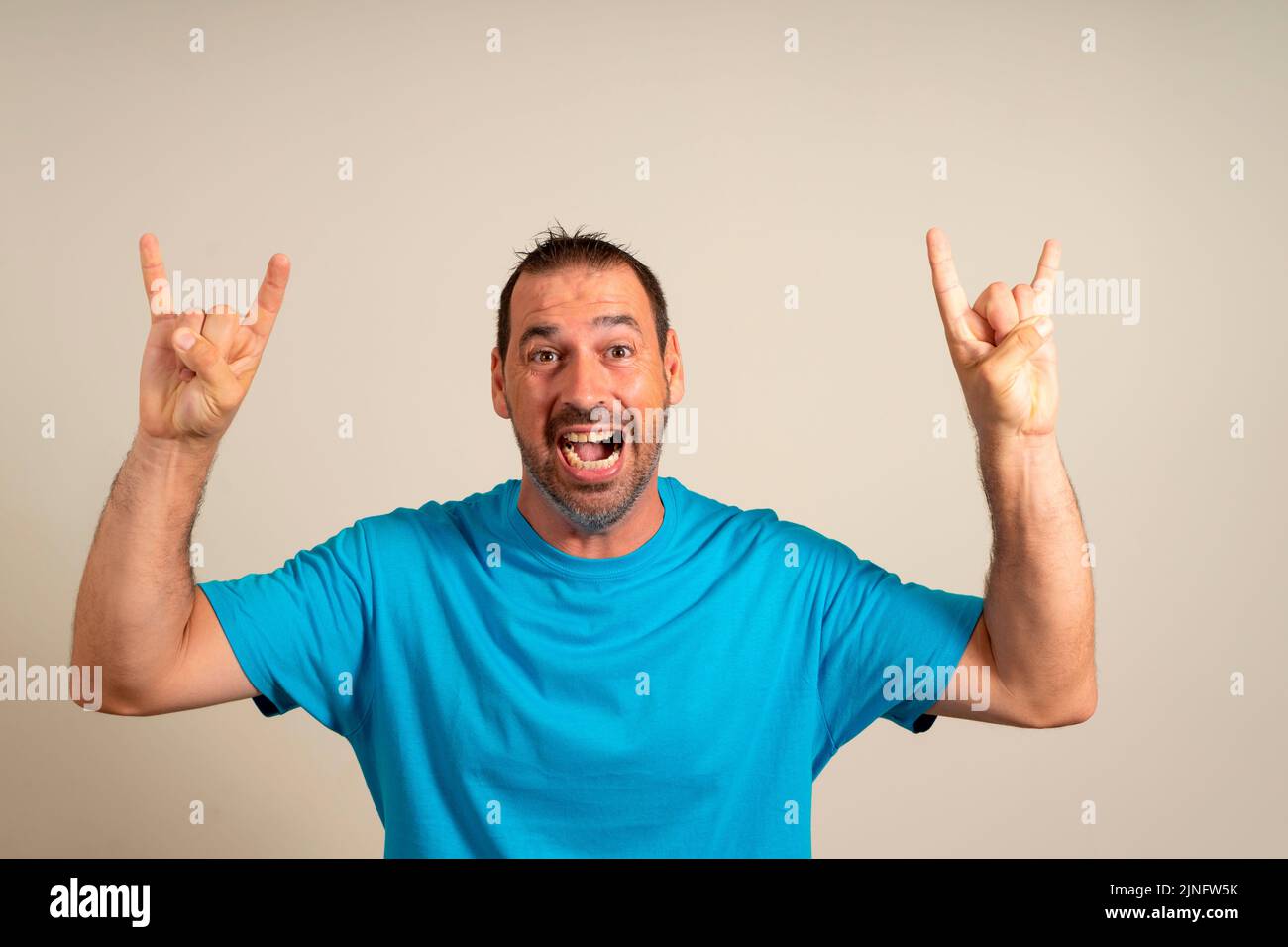 Rock fan gestures. Caucasian bearded man in blue t-shirt making rock ...