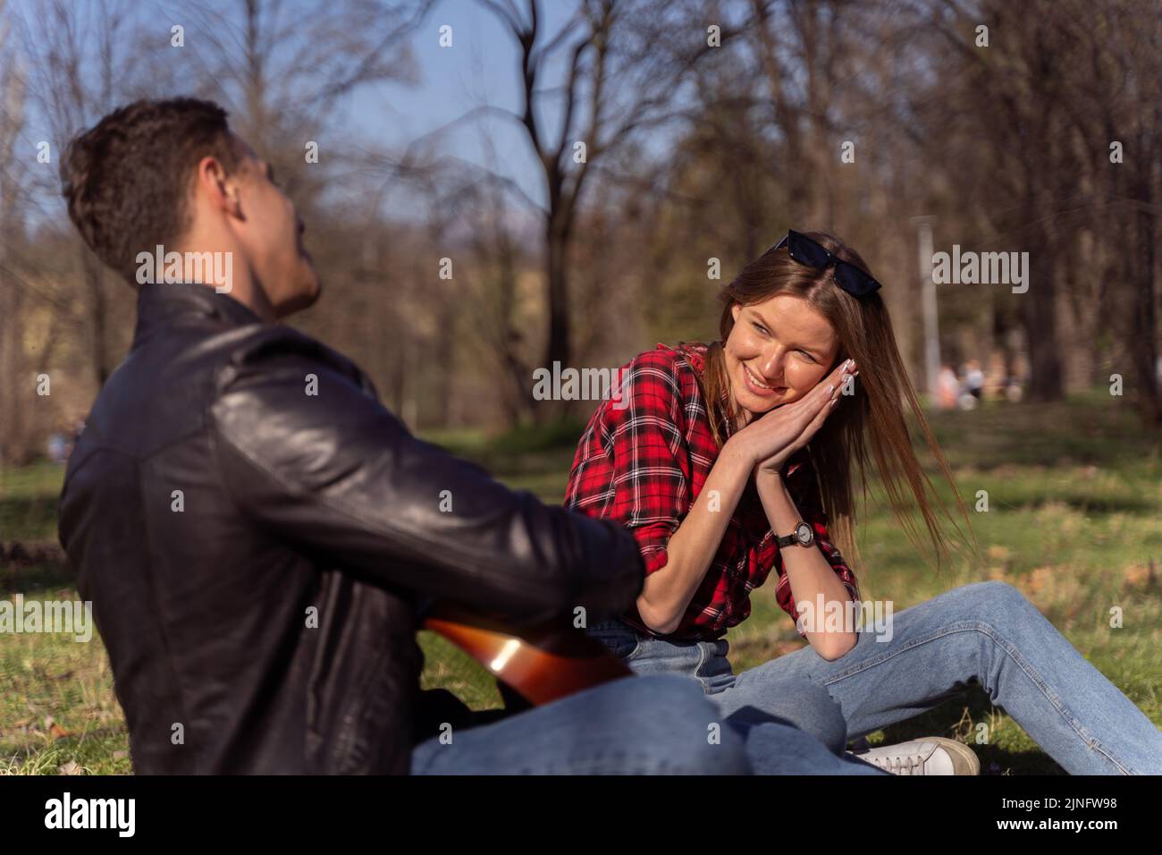 Cute couple sitting in the park while the girl is looking at her ...