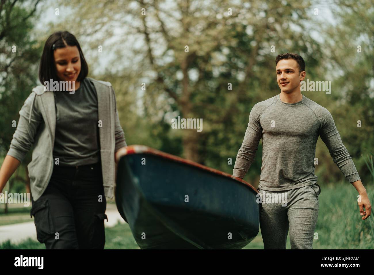 Close up of beautiful couple carrying a red kayak while walking in the ...