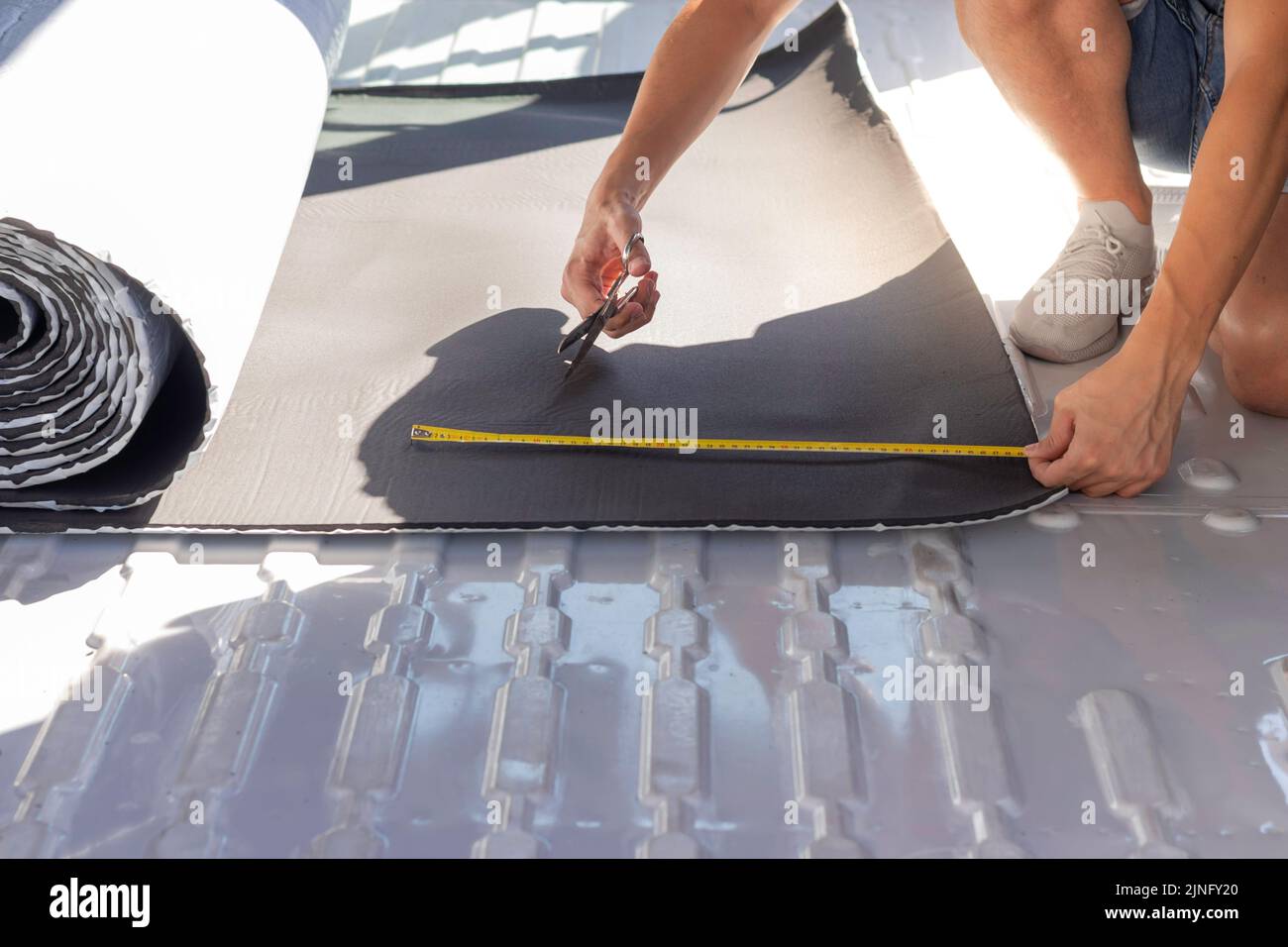 Unrecognizable young man measuring and cutting the rubber isolation ...