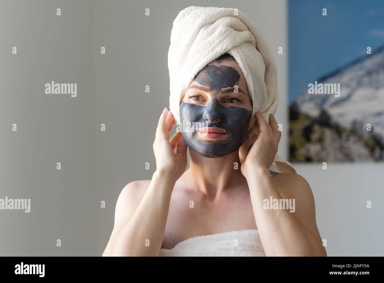 Woman removing facial dried clay mud mask with sponge in bathroom in ...