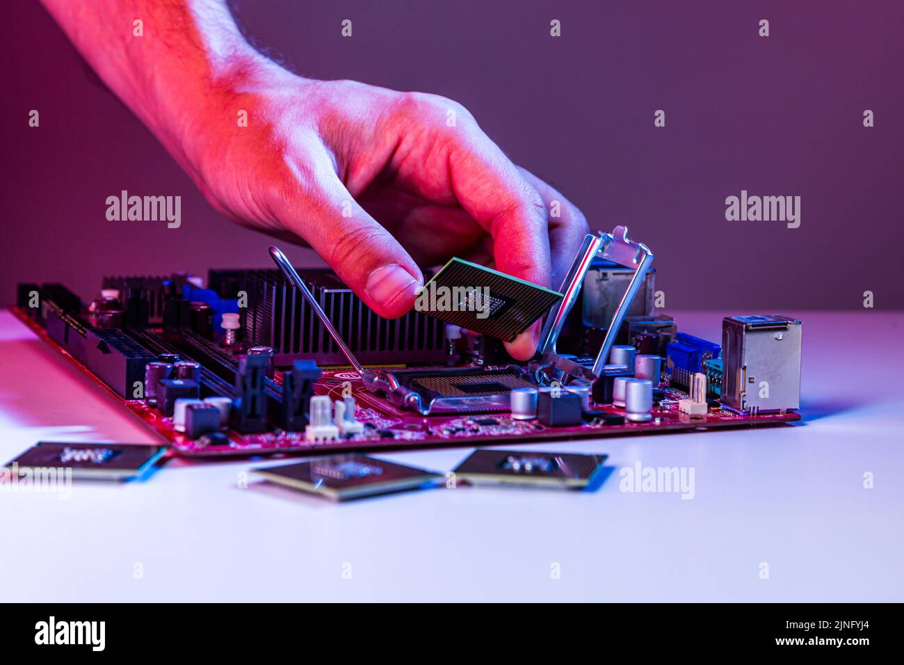 A man's hand inserts a processor into the motherboard socket Stock ...
