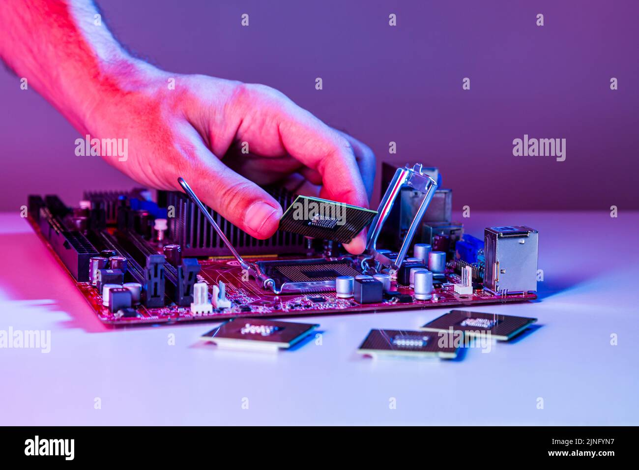 A man's hand inserts a processor into the motherboard socket Stock ...