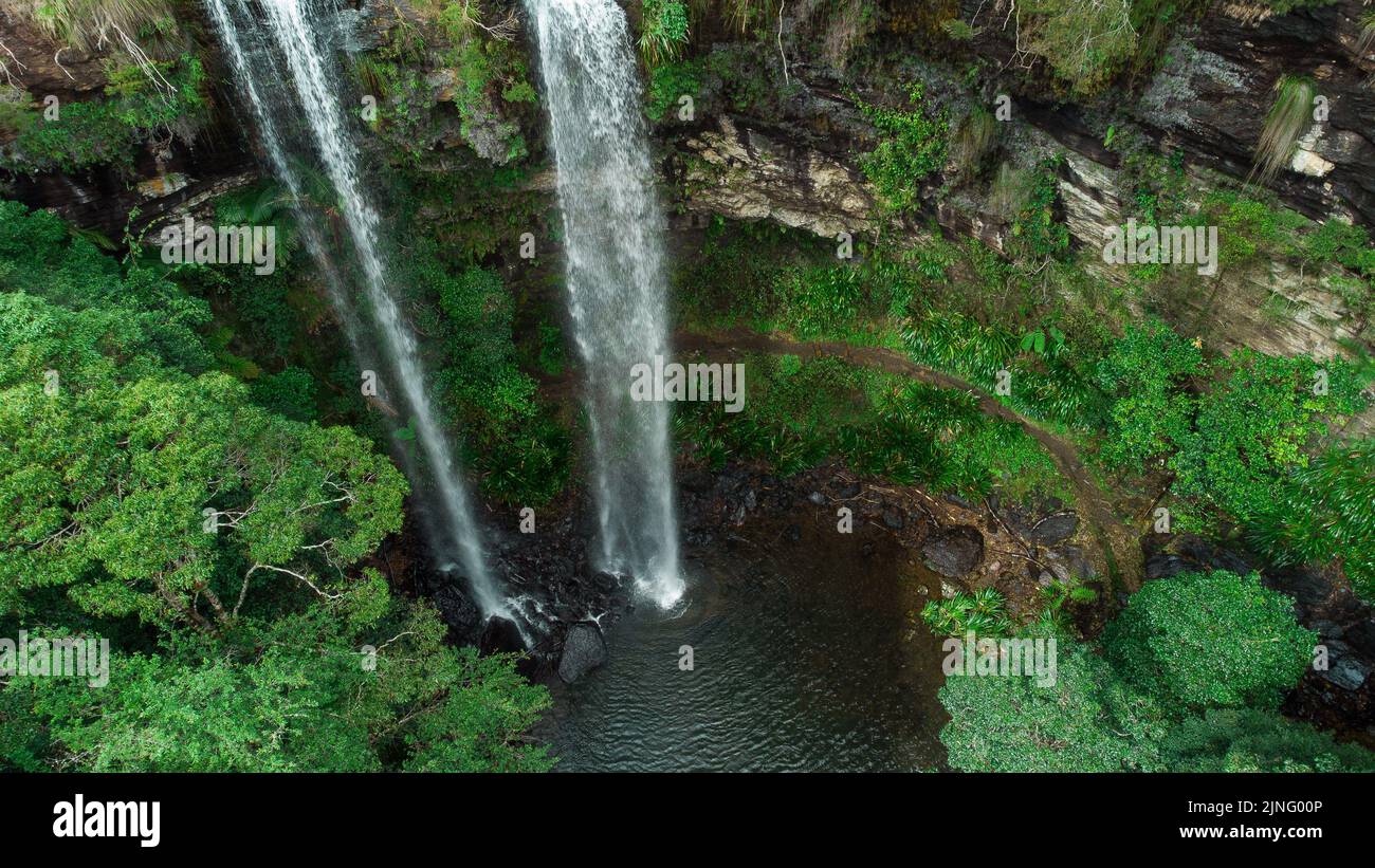 An aerial shot of a waterfall pouring surrounded by vegetation and ...