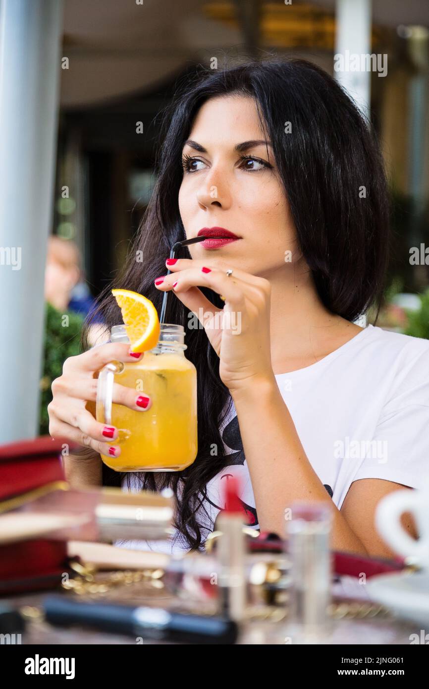 A charming woman drinking orange fresh at a coffee shop Stock Photo - Alamy