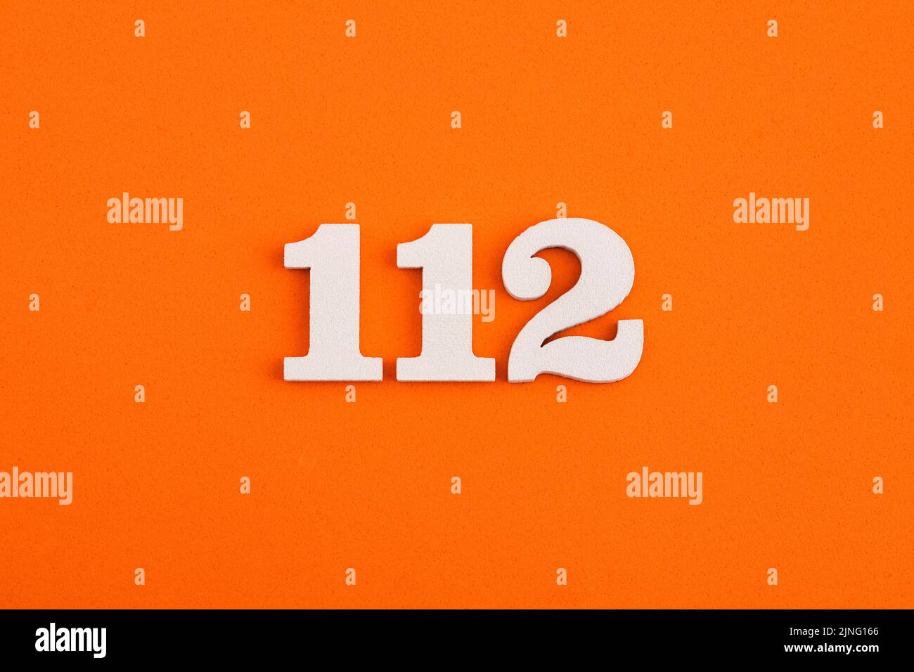 White wooden number 112 on eva rubber orange background Stock Photo - Alamy