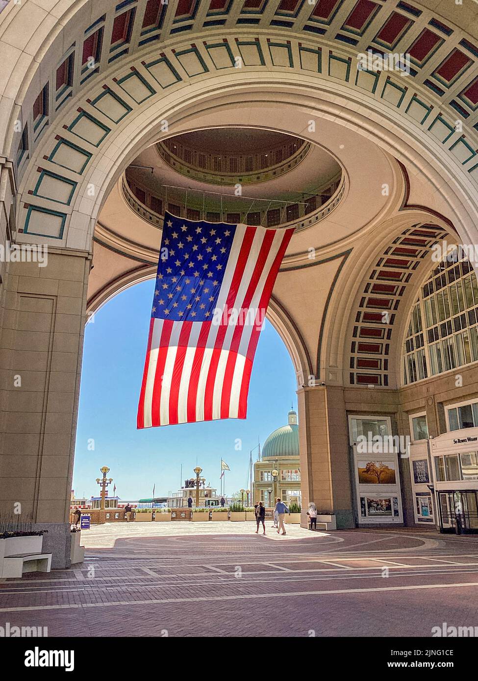 A giant American Flag hangs from the arch and buildings at Rowes Wharf ...