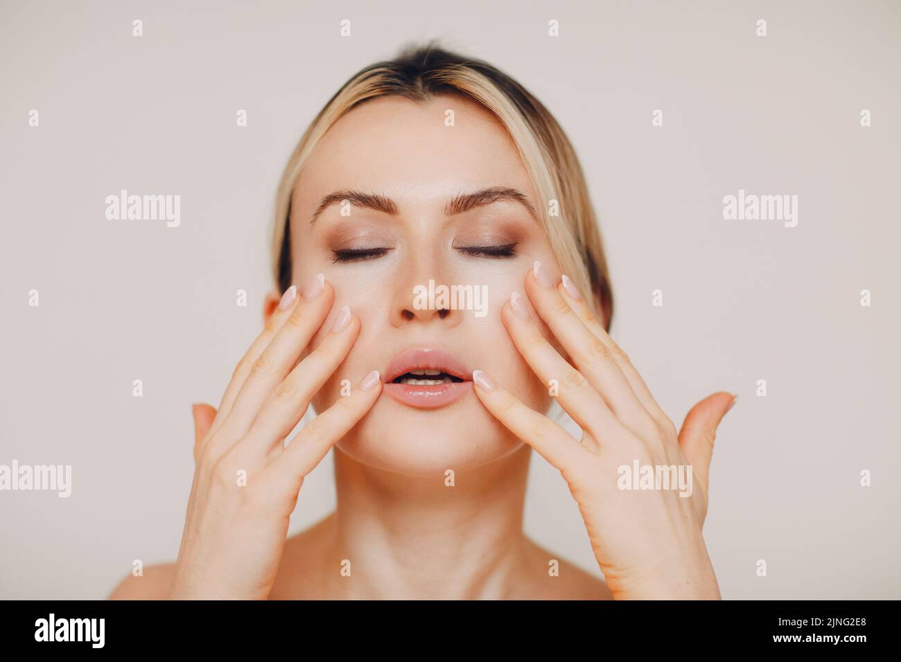 Young adult woman doing facial gymnastics self massage and rejuvenating ...
