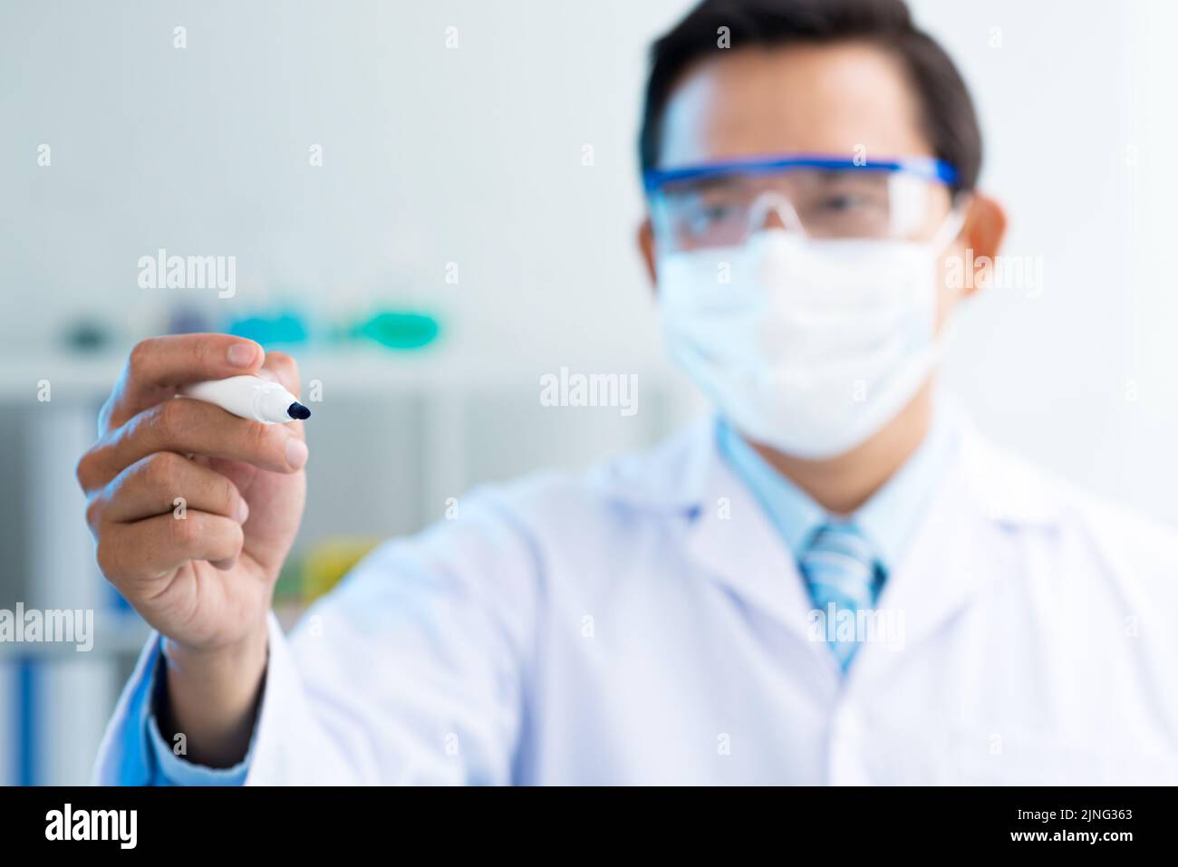 Close-up shot of confident Asian scientist wearing safety goggles and ...