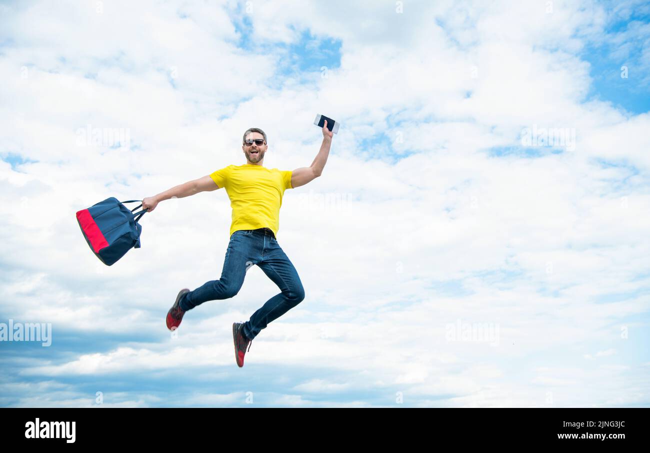 Active guy jumping with travel bag midair sky background, copy space ...