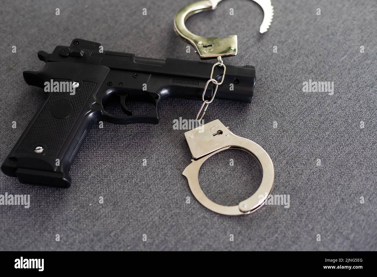 Black gun and metal handcuffs lie on the black background. Private ...