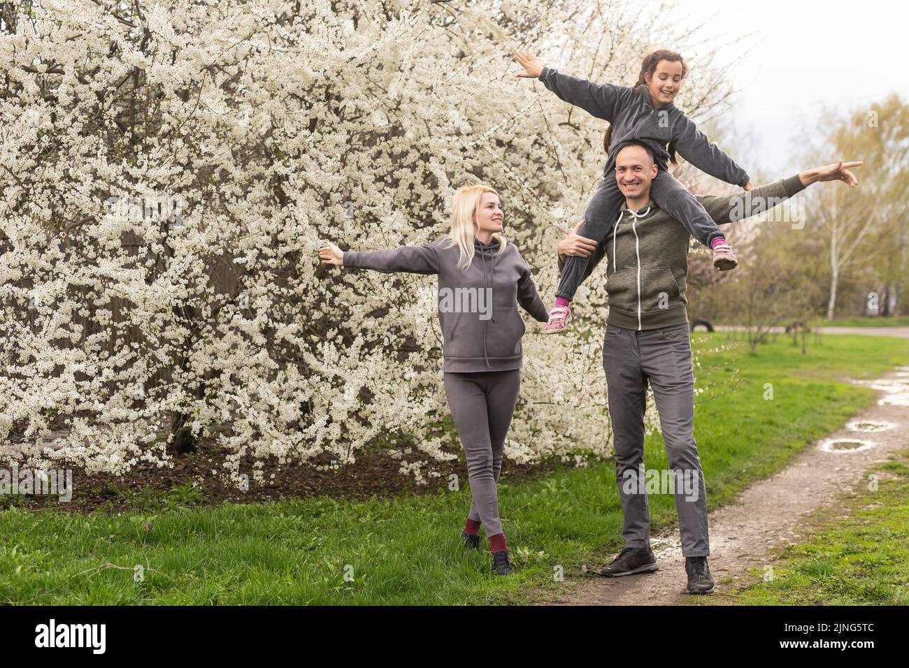 family having fun with flowering tree in blooming spring garden Stock ...