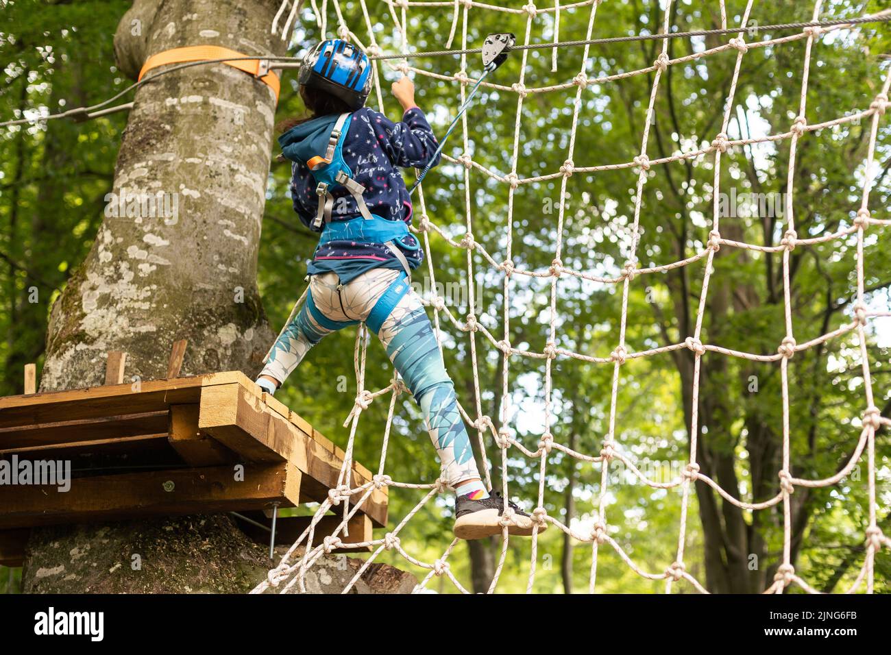 Little girl preschooler wearing full climbing harness having fun time ...