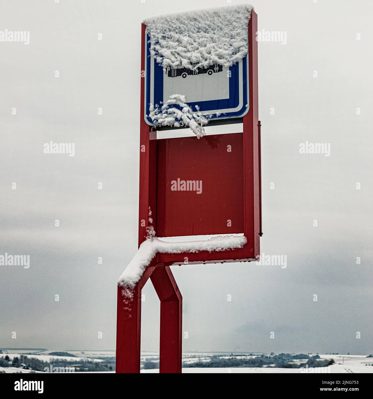 A view of a red bus stop sign covered with snow Stock Photo - Alamy