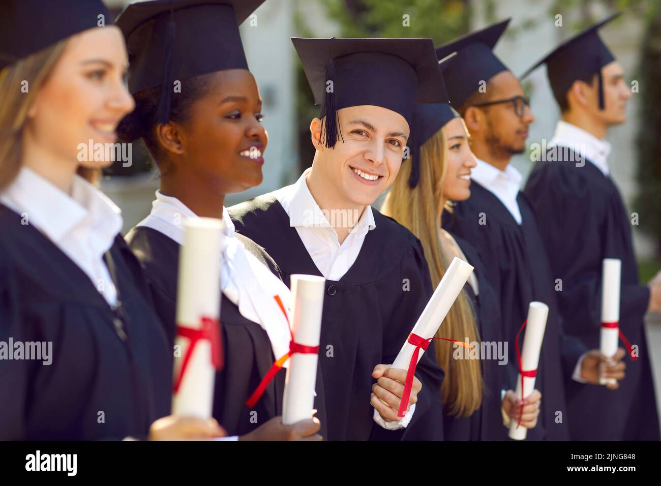 Young smiling man graduate participates in graduation ceremony stands ...
