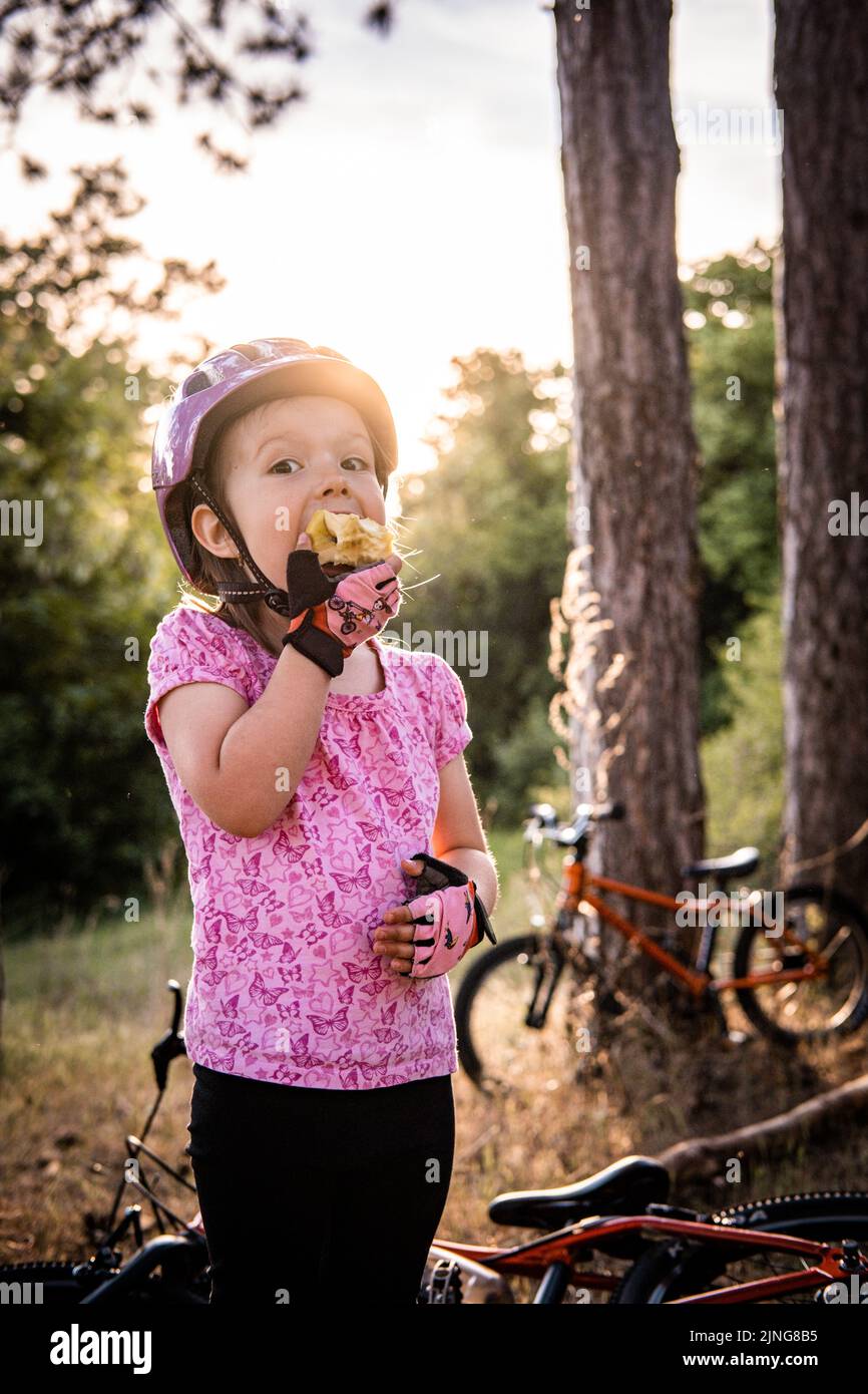 a little girl behind a bicycle eating an apple Stock Photo - Alamy