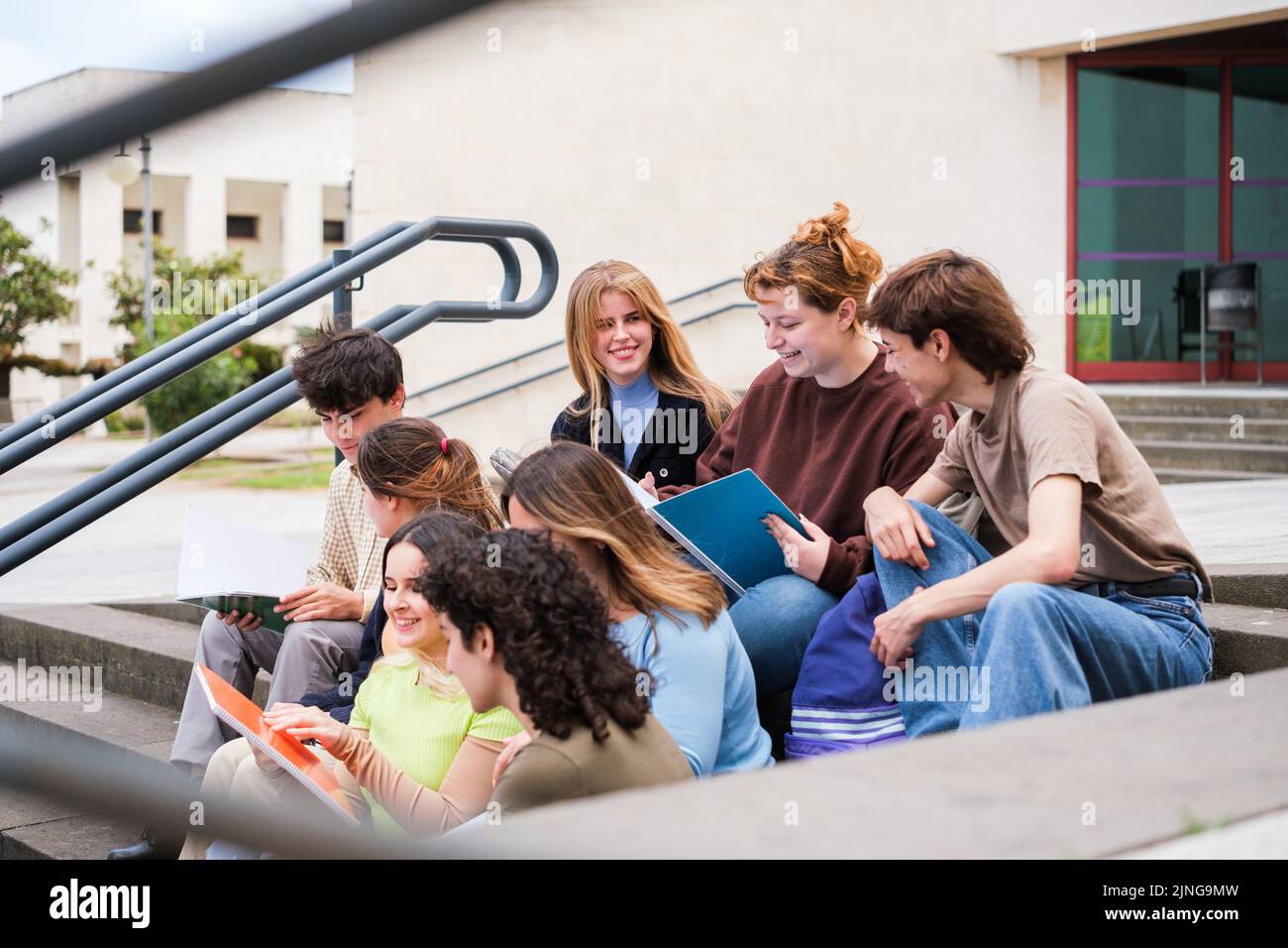 Group of students sitting on the stairs exchanging books Stock Photo ...
