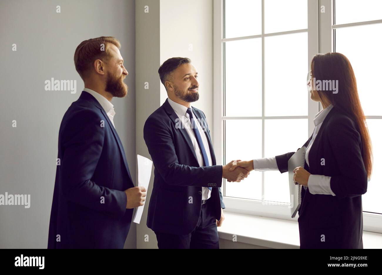 Happy business people meeting, making a partnership deal and exchanging ...