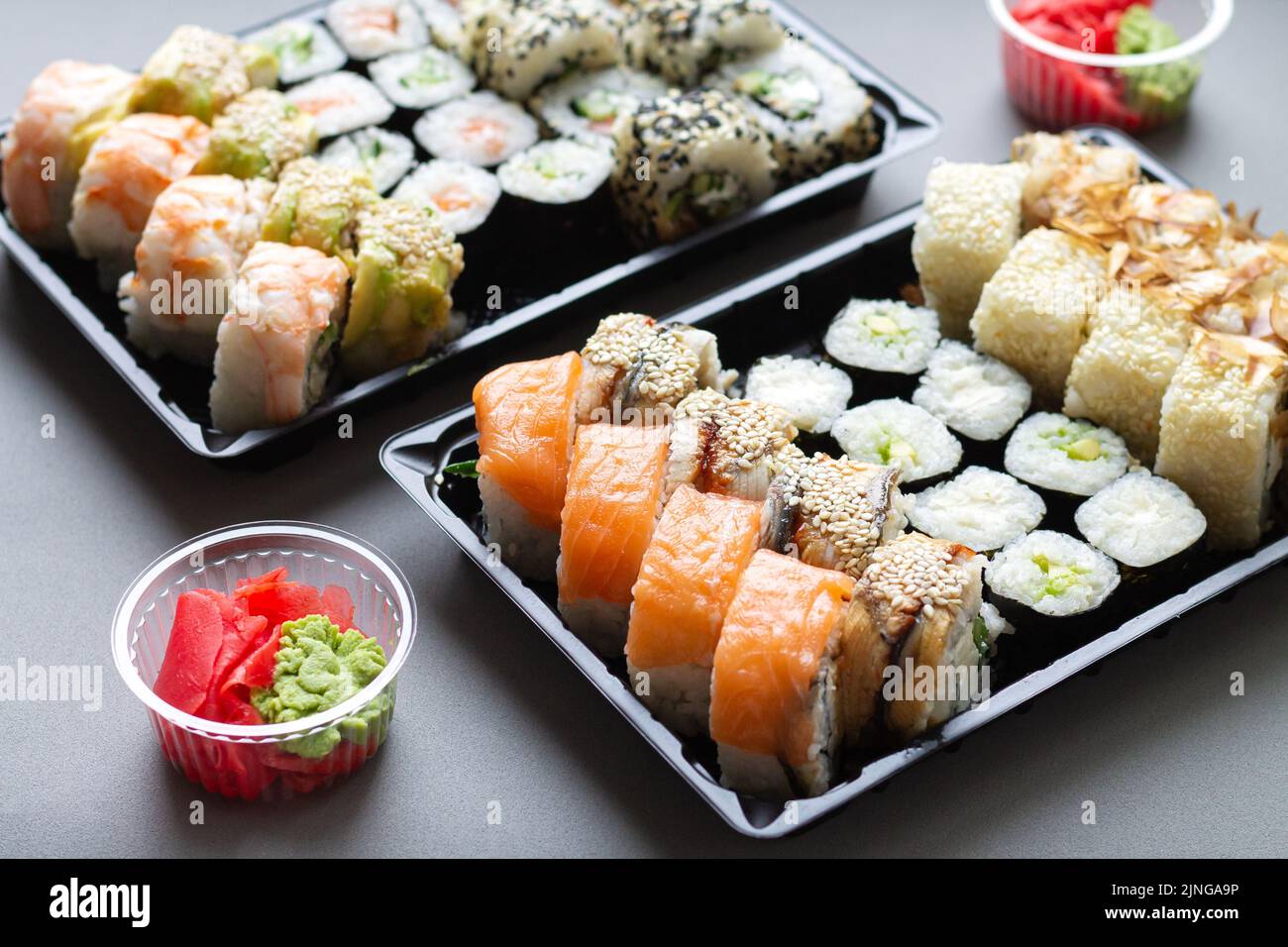 Big sushi rolls set in black plastic box for take away on gray ...