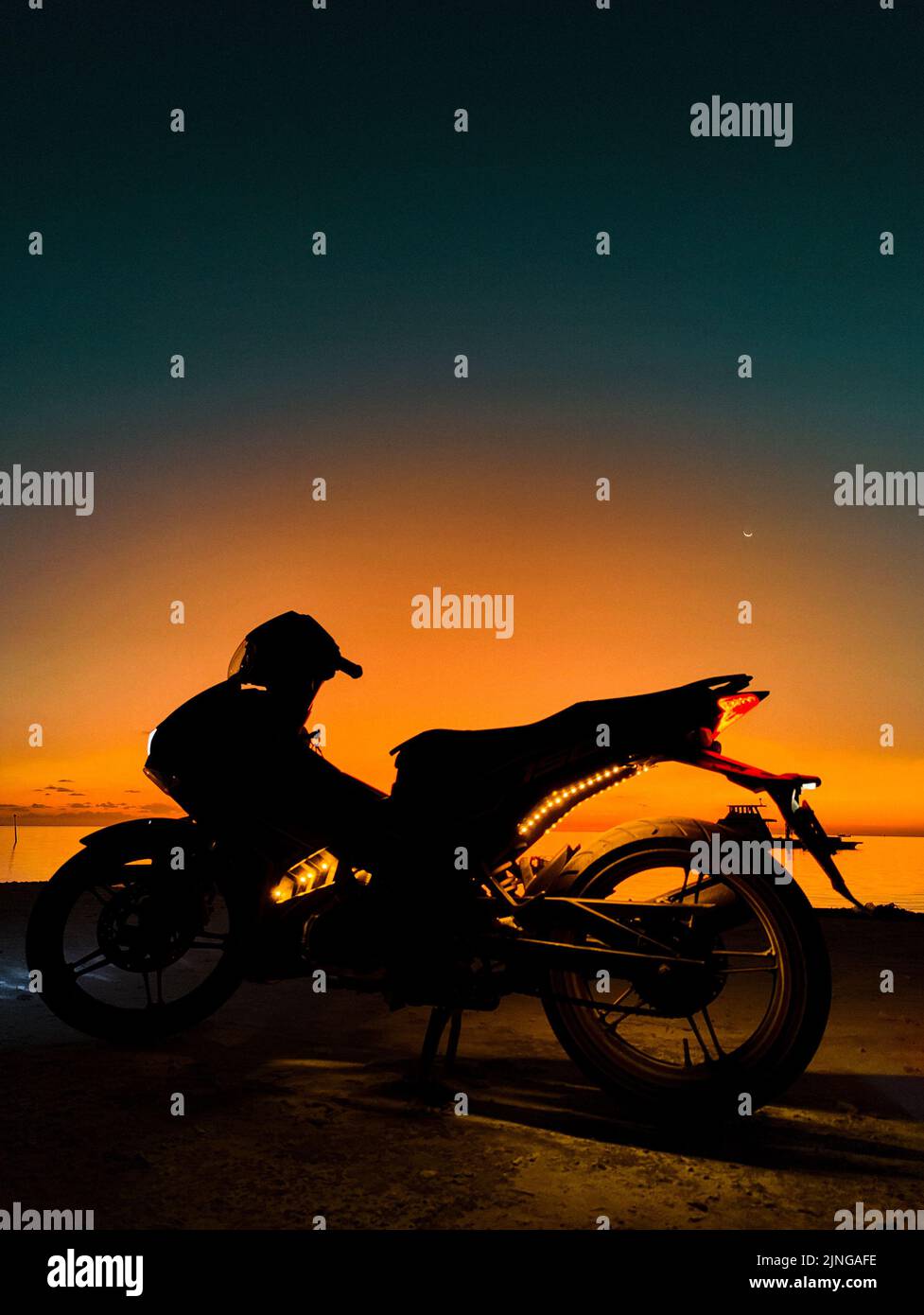 A vertical silhouette of a high-speed motorcycle with sunset in the ...