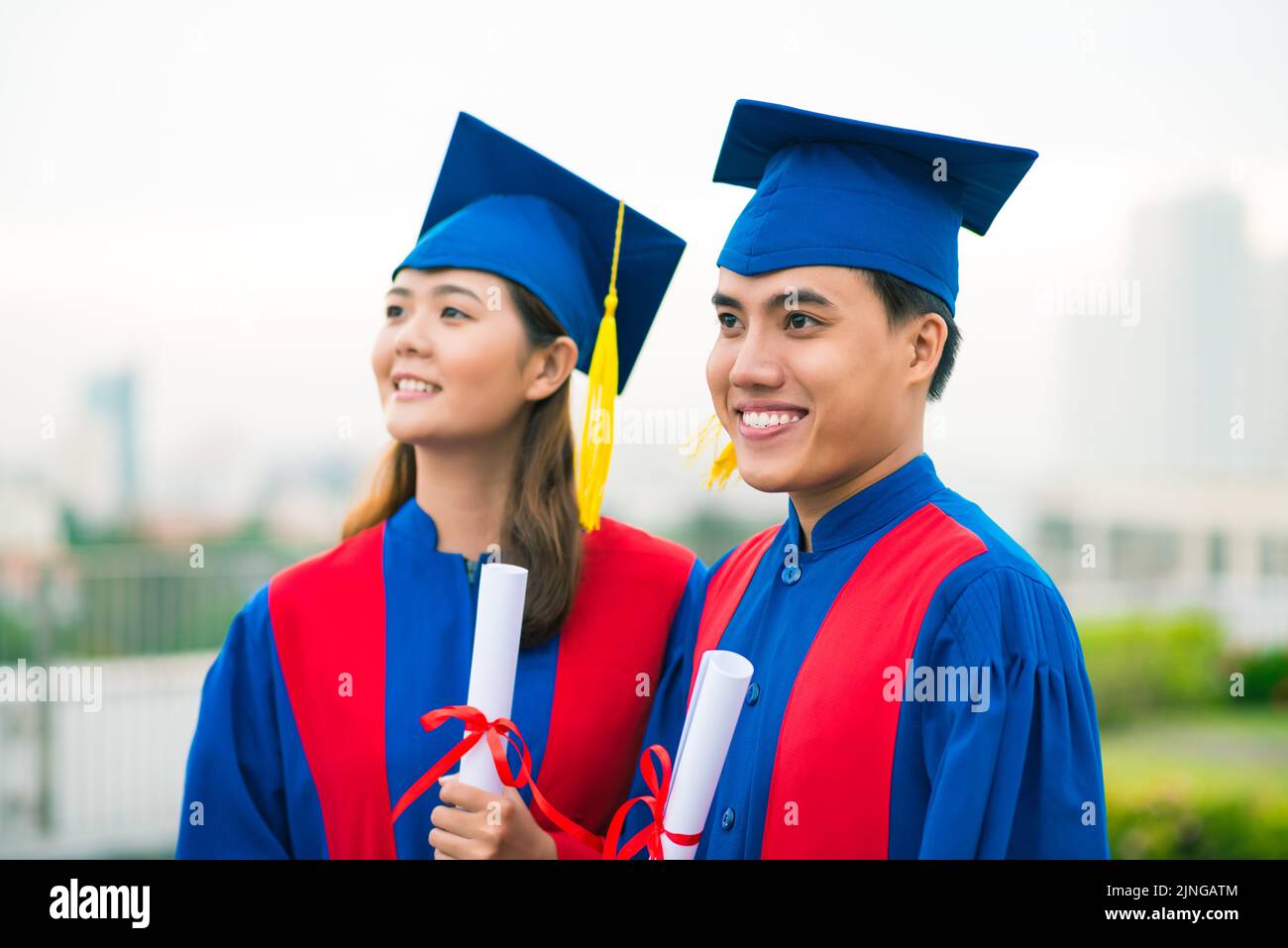 Happy Vietnamese students in graduation gowns standing outdoors Stock ...