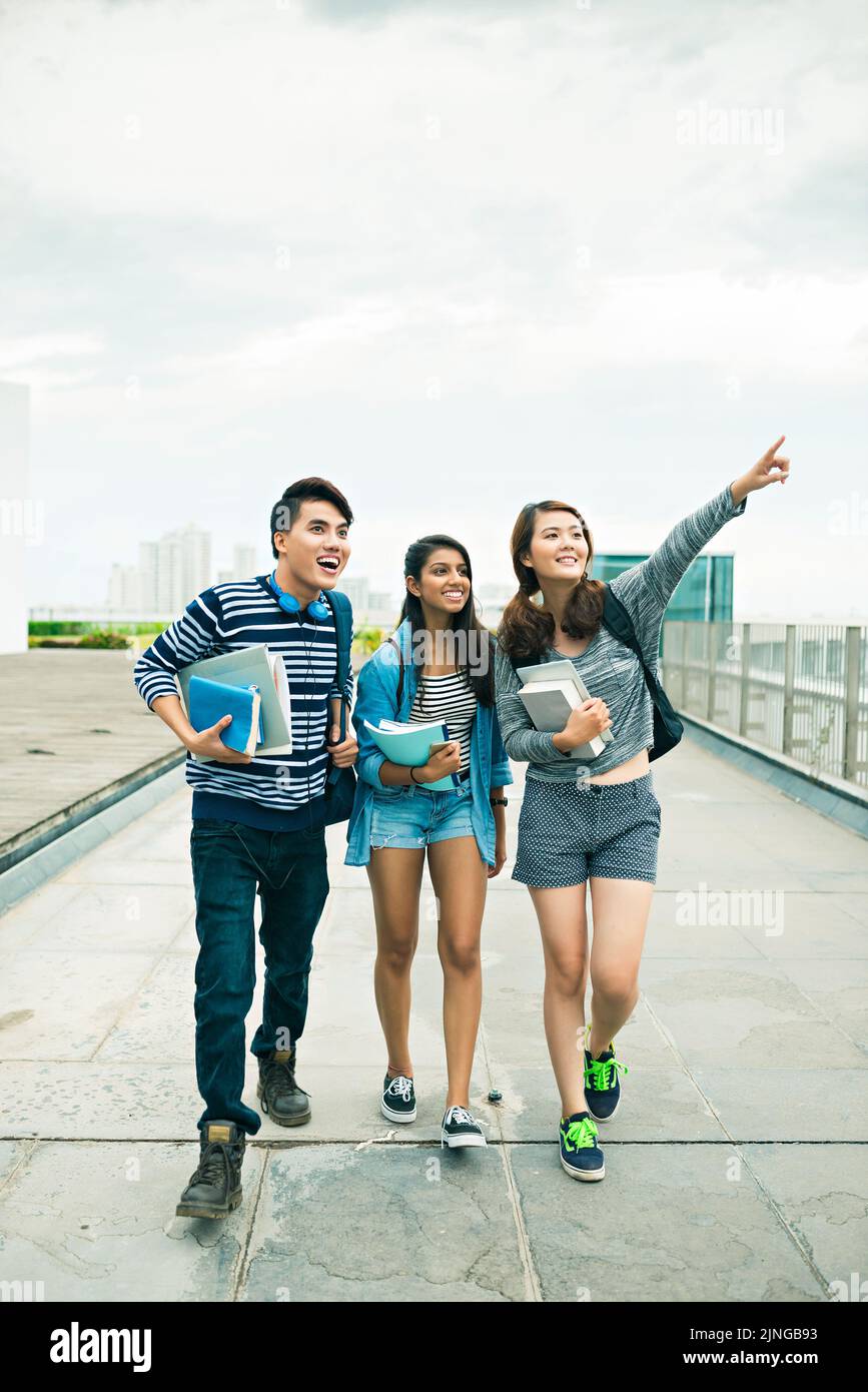 Group of excited Vietnamese college students with books looking at ...