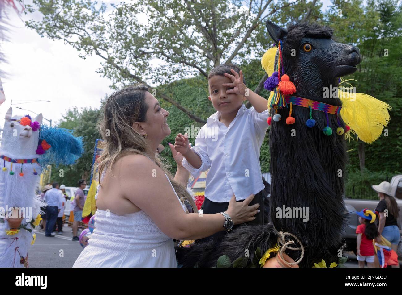 A vendor and her son at a stand with a wooden animal statue. At the ...
