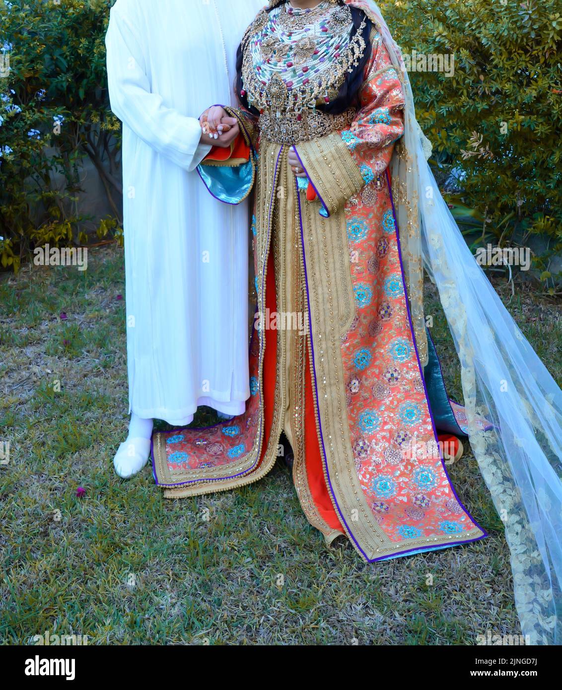 Moroccan wedding. A groom wearing a djellaba holds his bride who is ...