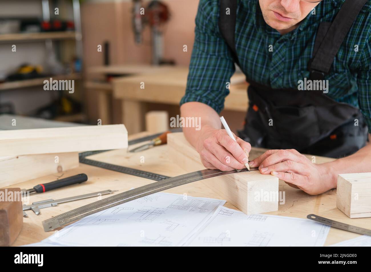 A carpenter measures wooden planks and makes marks with a pencil in a ...