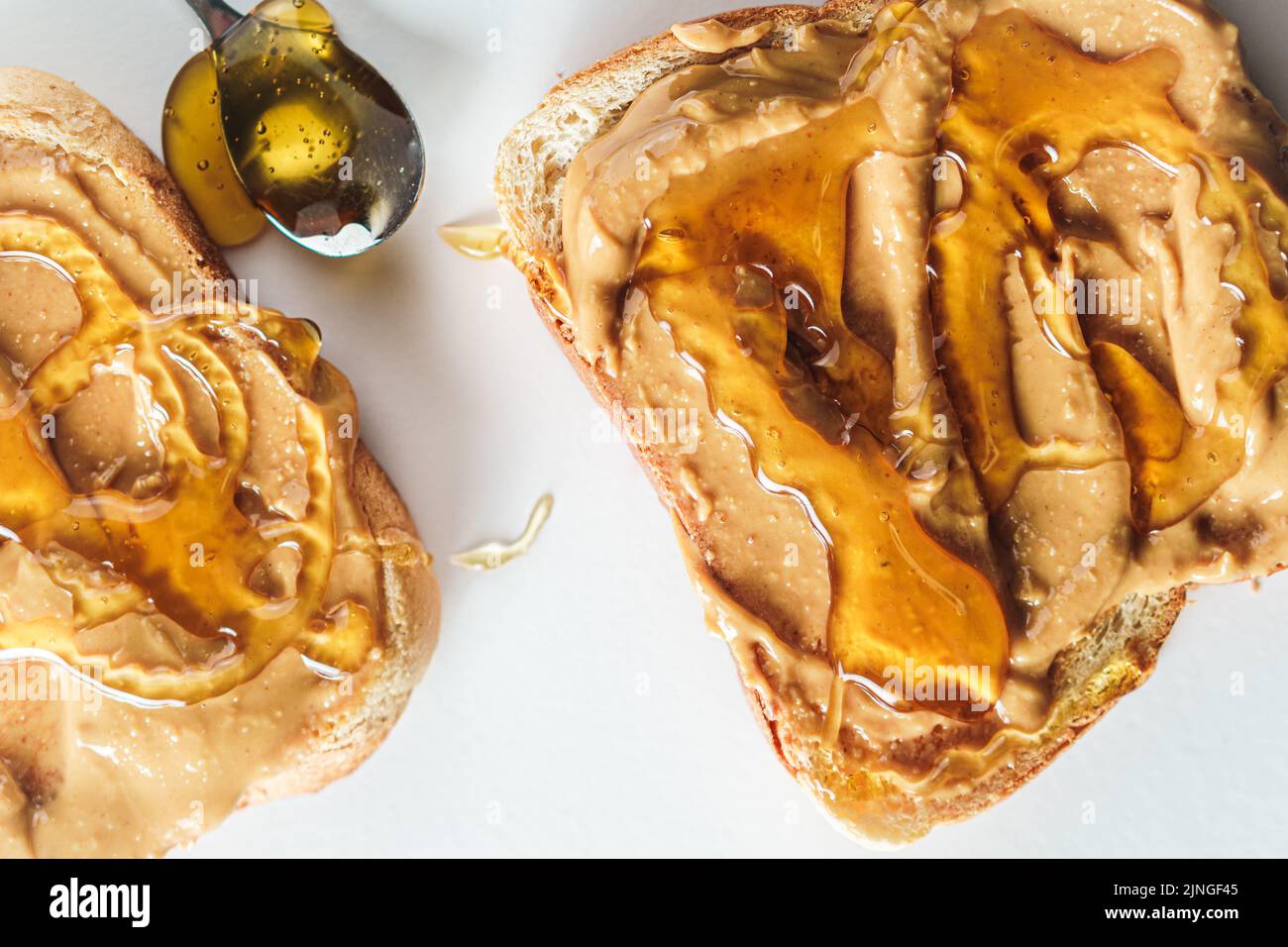 A top view of peanut butter sandwiches with honey trickled on a white ...