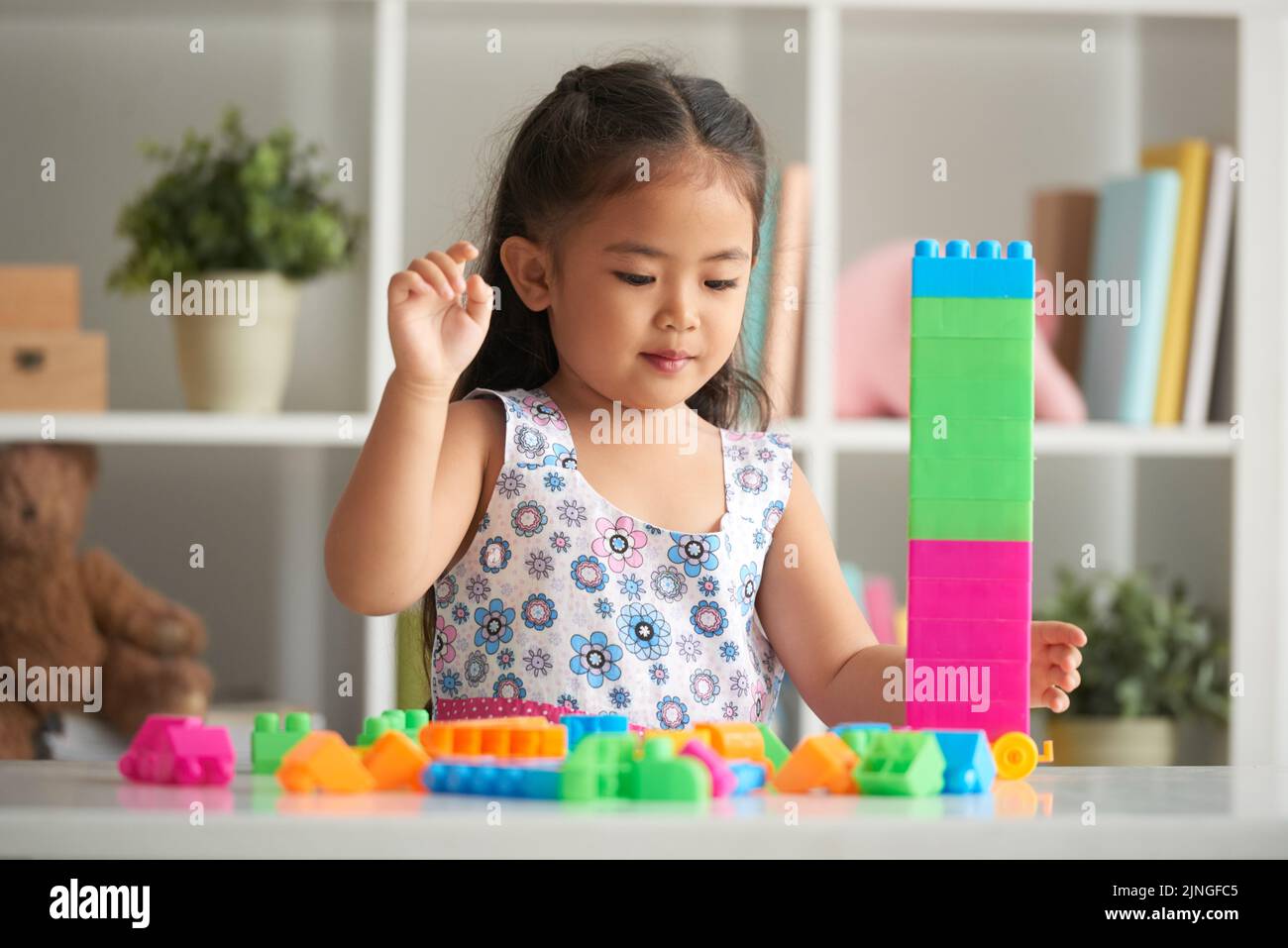 Little girl building with bright plastic cubes Stock Photo - Alamy