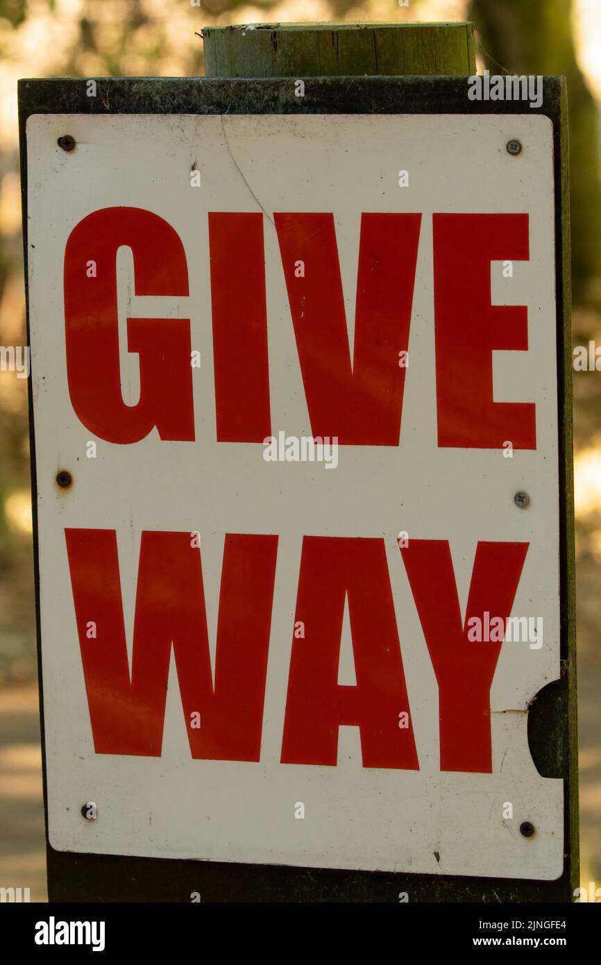 A vertical shot of a sign saying give way in block red letters Stock ...