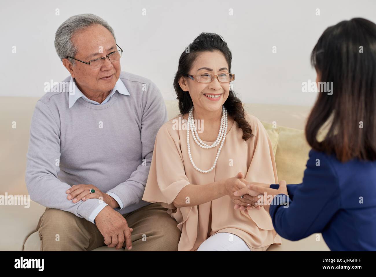 Friendly interior designer greeting her senior clients with handshake ...