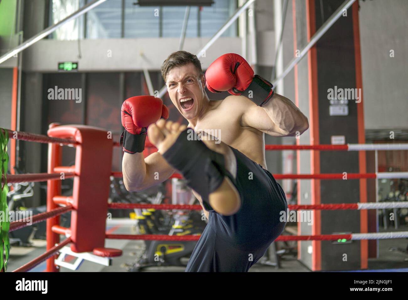 A Caucasian Kick boxer kicking with his leg in front of the camera ...