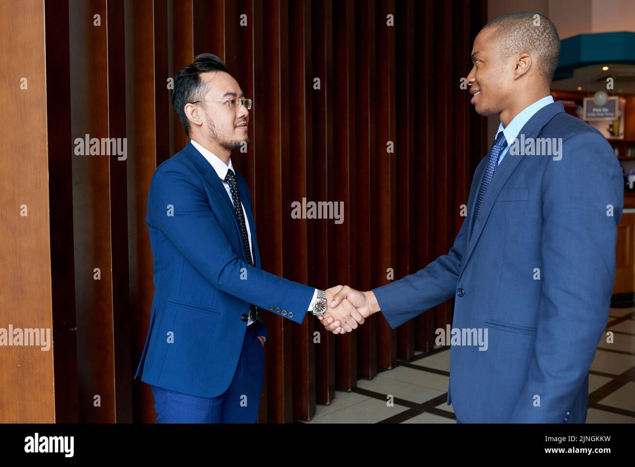 Cheerful coworkers shaking hands to greet each other Stock Photo - Alamy