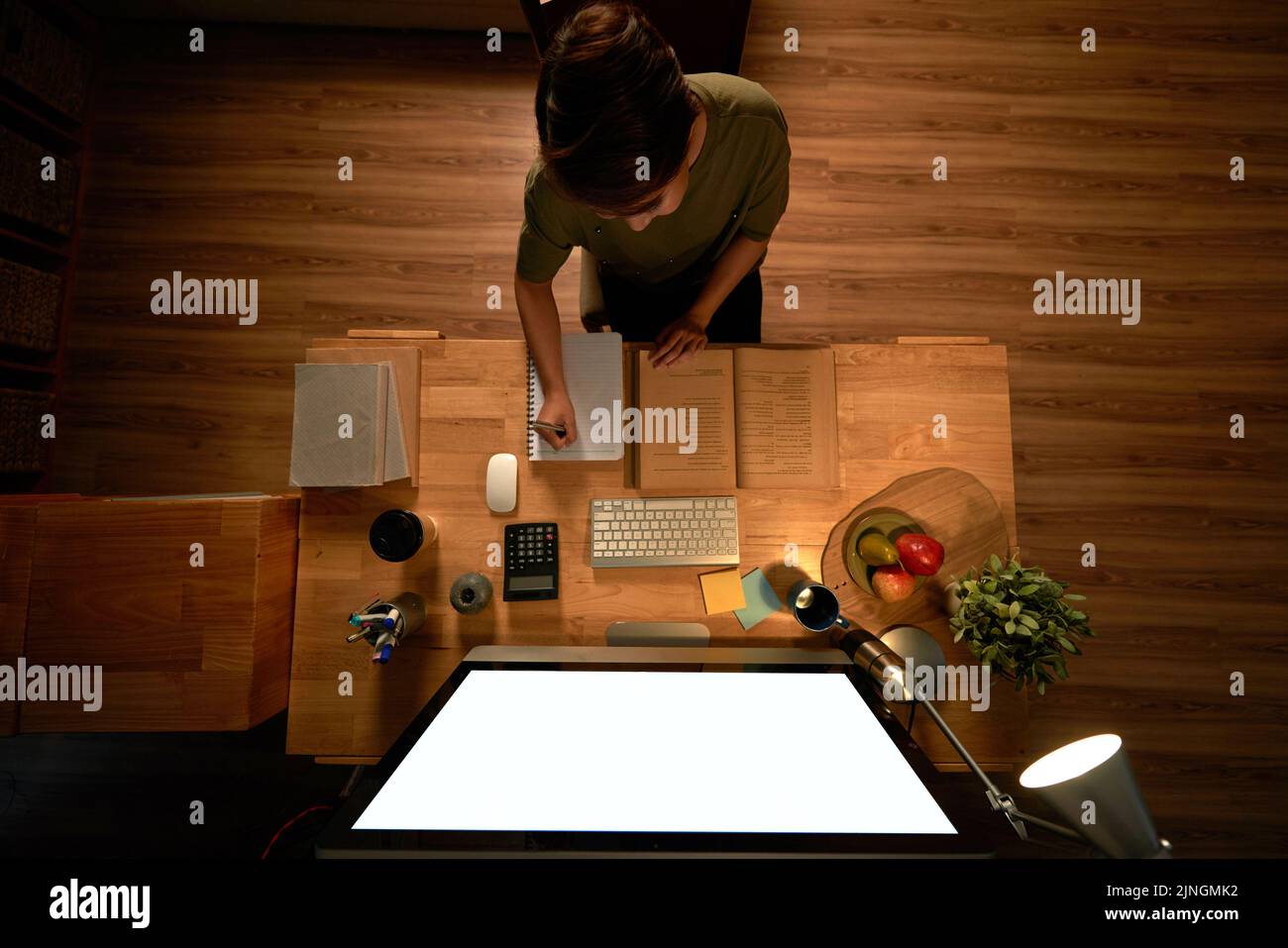 Female university student doing homework at her table late at night ...