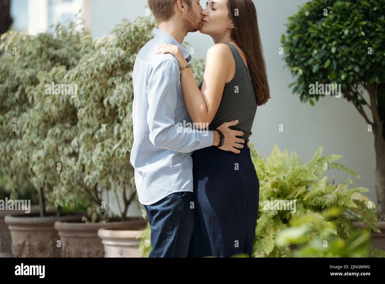Beautiful young couple kissing near decorative potted plants Stock ...