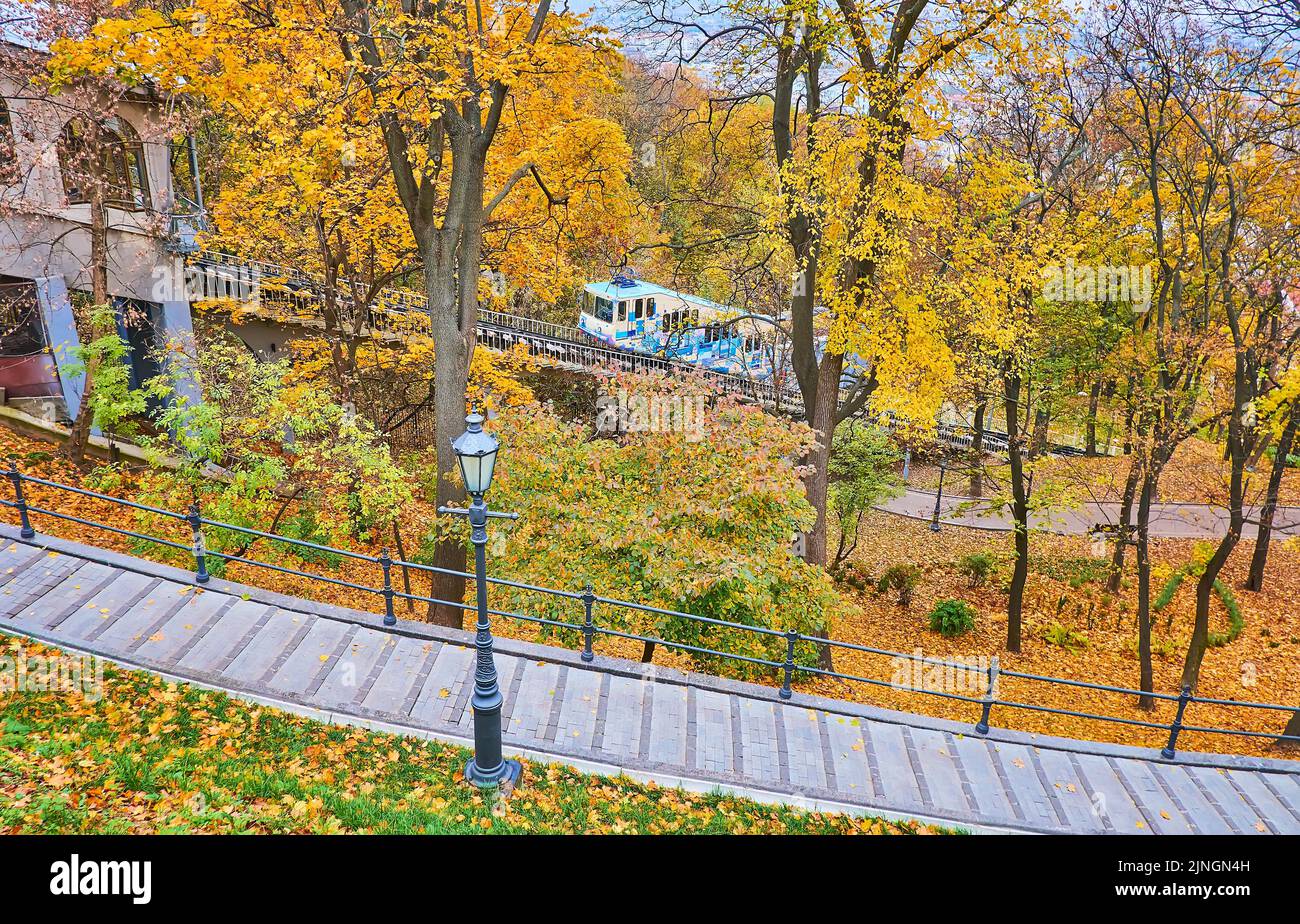 The wagon of Kyiv Funicular is seen behind the yellow autumn trees of ...