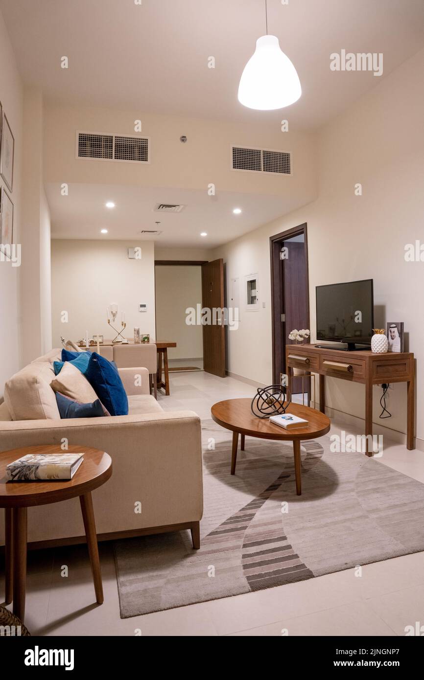 A living room with a television set, chair, round tables, and a sofa ...