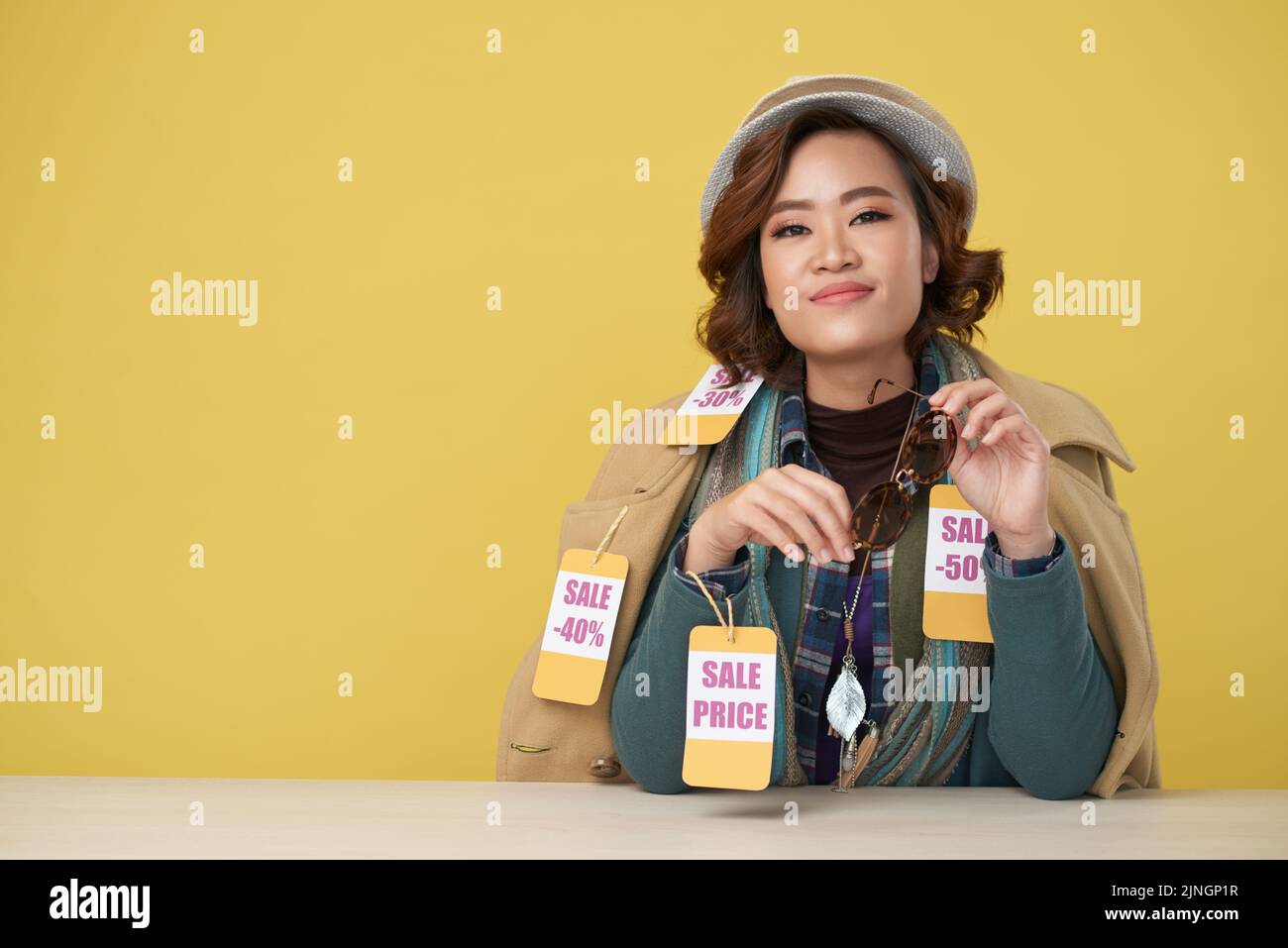Beautiful Asian Woman Wearing Clothes With Sale Labels Posing On Yellow