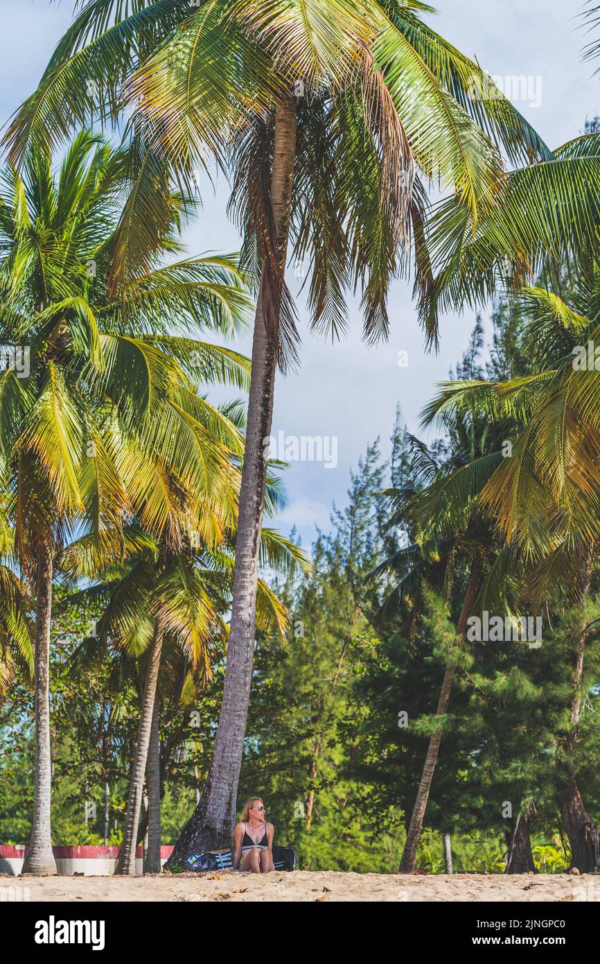 A vertical shot of a blonde Caucasian woman sitting on the Luquillo ...