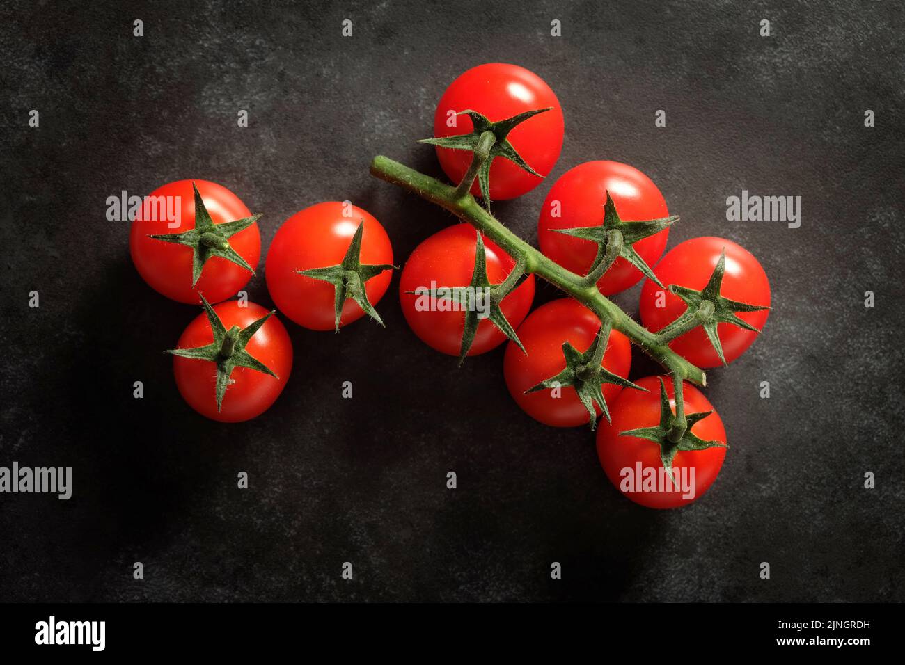 Cherry vine tomatoes shot from above on dark background Stock Photo - Alamy