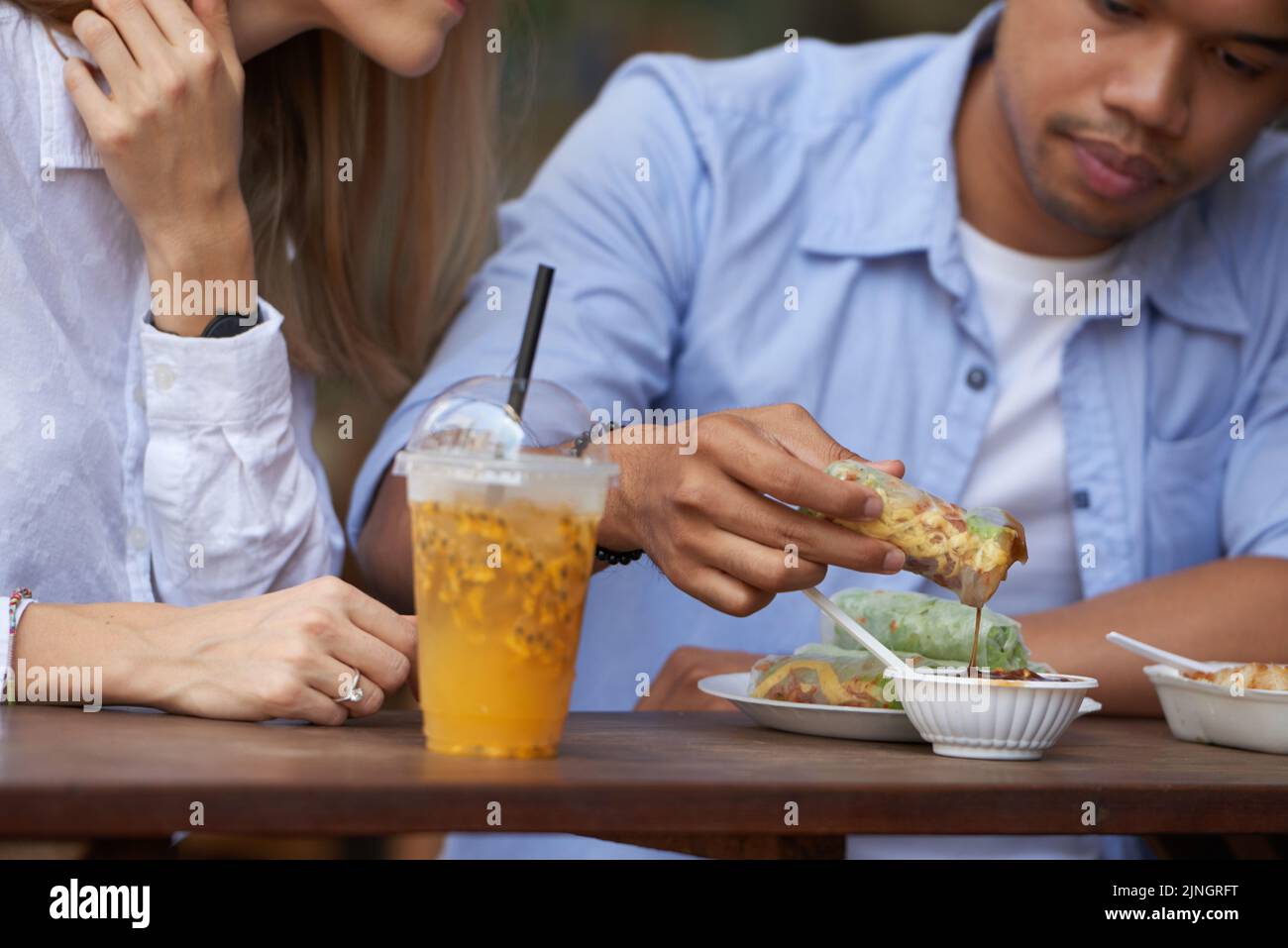 Man dipping spring roll into sauce while having lunch with his ...