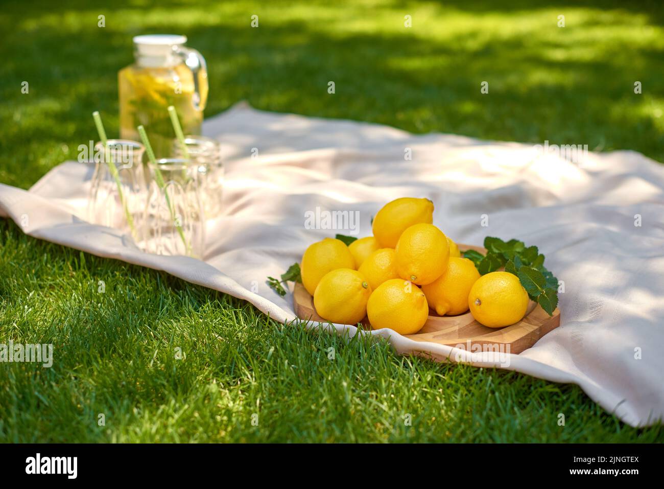 summer lemonade picnic with glass jug of cool drink on light bedding on ...