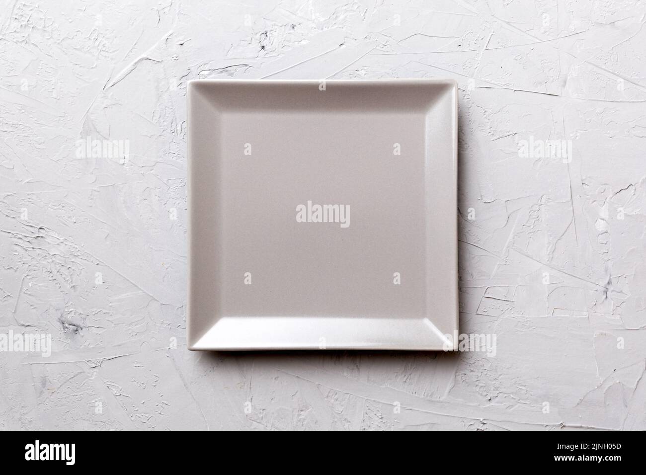 Top view of empty square plate on cement background. Empty space for ...